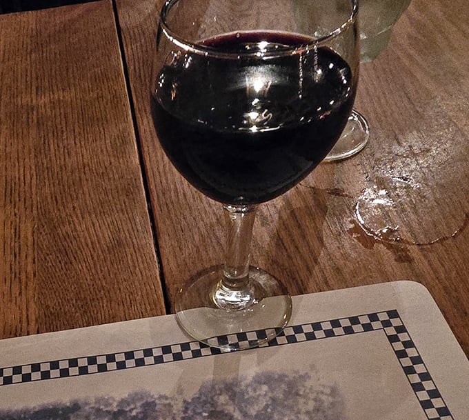 A glass of red wine catching the warm glow of candlelight &ndash; the perfect companion for conversations that stretch pleasantly into the evening.