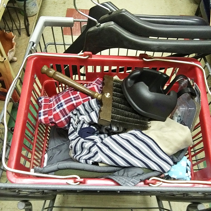 Shopping cart archaeology in progress! Each layer reveals different eras&mdash;plaid shirts, brass candlesticks, and is that a ladle from the 1970s?