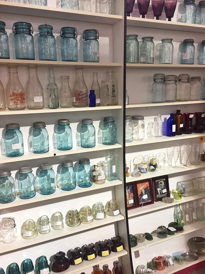 The blue-green glow of vintage Mason jars creates an underwater effect&mdash;each shelf a tide pool of American glass history waiting to be collected.