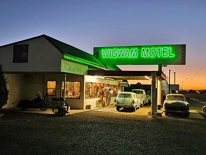 As night falls, the neon glow transforms the Wigwam Motel into a beacon of mid-century nostalgia that Edward Hopper would have loved.