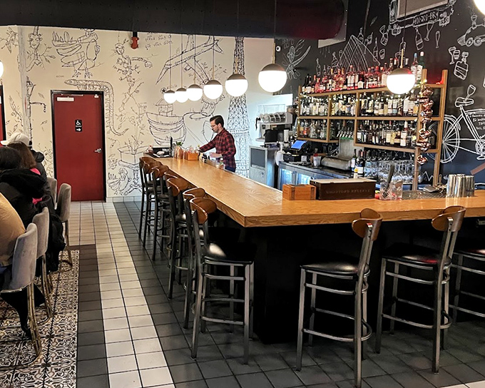 The bar isn't just serving drinks; it's staging liquid theater against a backdrop of playful illustrations and warm wood tones.