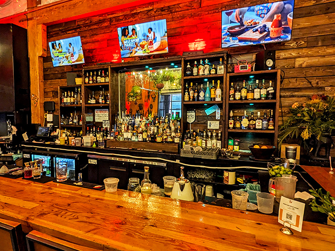 The bar at AKADI isn't just stocked with spirits &ndash; it's a liquid library of possibilities, backed by warm wood that glows like sunset.