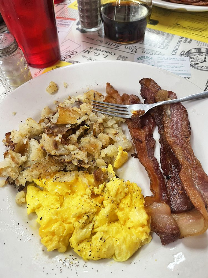 The breakfast trinity &ndash; golden eggs, crispy hash browns, and bacon cooked to that perfect point between chewy and crisp. Morning salvation on a white plate.
