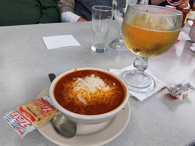 A bowl of chili topped with melted cheese alongside a frosty beer. Some combinations are timeless for a reason—this is winter comfort in its purest form.