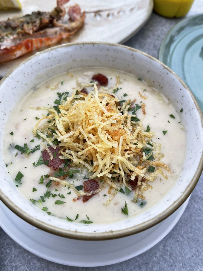 This isn't just clam chowder – it's a warm hug in a bowl. Creamy, bacon-studded comfort topped with crispy potato strands for textural genius.