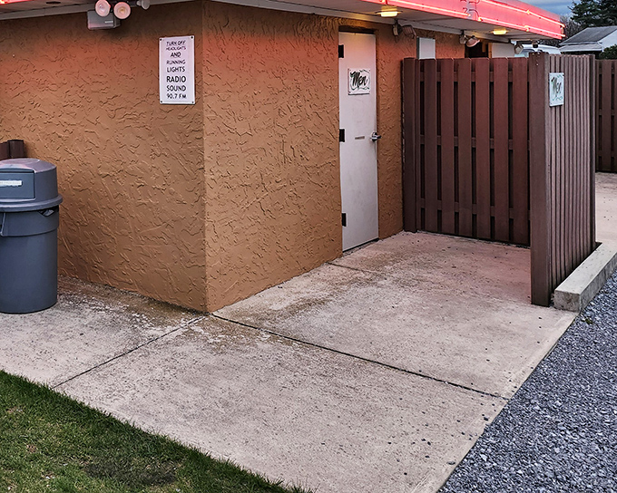 The comfort station's warm glow welcomes moviegoers during intermission, a necessary pitstop between double features.