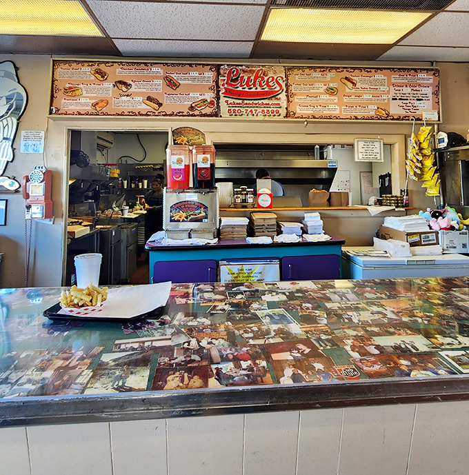 At the counter, decades of photos create a mosaic of memories. This isn't corporate d&eacute;cor &ndash; it's a community scrapbook with sandwich service.