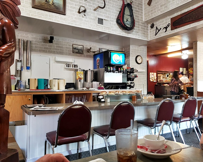 Counter seating where regulars perch, coffee cups perpetually filled, watching the morning dance of short-order cooking.