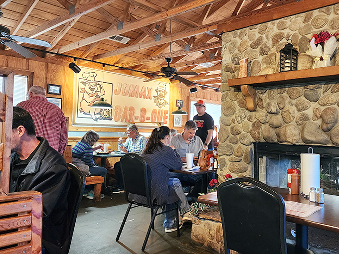 The dining room hums with the universal language of good eating. That stone fireplace isn't just for show &ndash; it's the heart of this BBQ sanctuary.