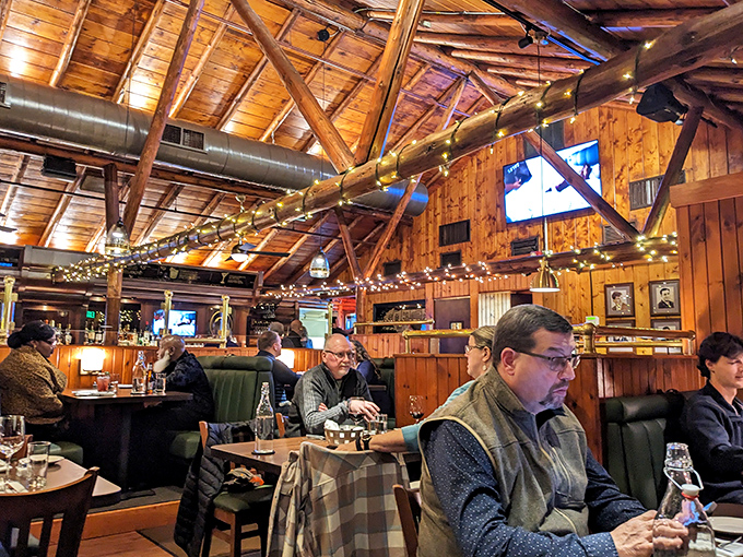 The dining room buzzes with conversation and clinking glasses, where strangers become friends under the warm glow of string lights and wooden beams.