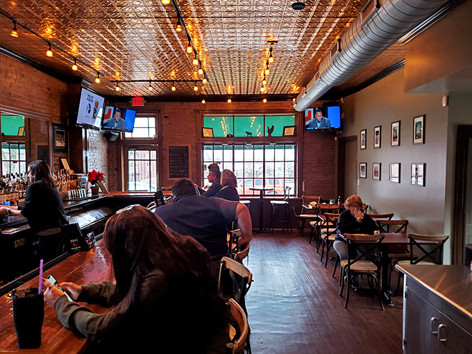 The warm glow of pendant lights against exposed brick creates the perfect backdrop for the burger epiphanies happening at these tables.