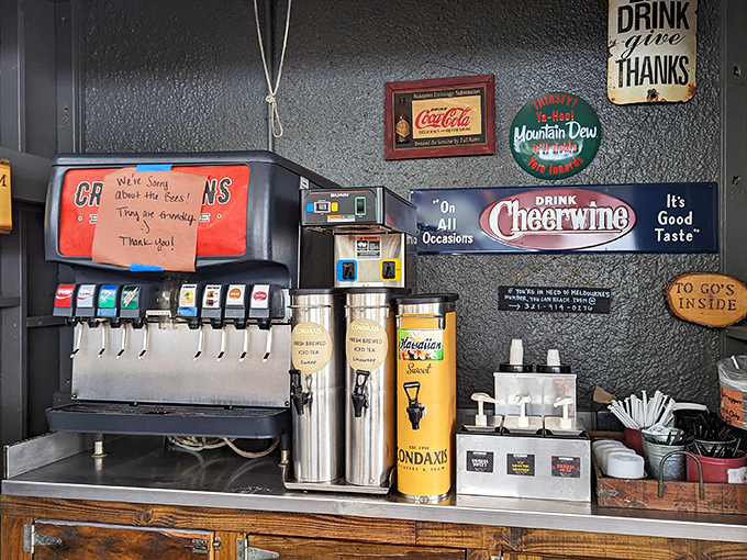 The drink station wall—where vintage signs remind you that washing down great barbecue is a tradition as old as barbecue itself.