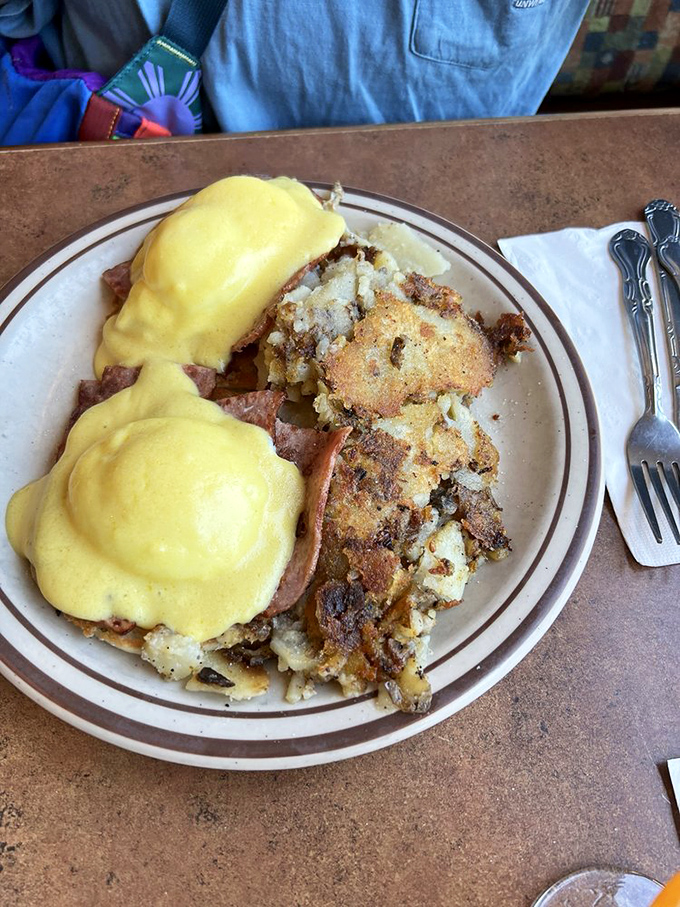 Eggs Benedict: where hollandaise sauce flows like liquid gold over perfectly poached eggs and crispy potatoes stand guard nearby.