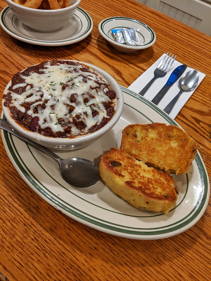 Chili that looks like it's been simmering since breakfast, topped with melted cheese and served with grilled bread for proper dipping.
