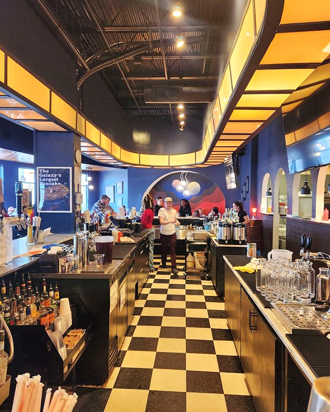 The checkered floor leads you into the heart of diner operations&mdash;where magic happens under the warm glow of that stunning curved ceiling installation.