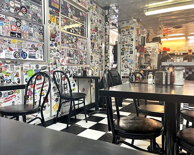 The black and white checkered floor and sticker-covered walls create the perfect backdrop for late-night philosophical discussions or early morning recovery missions.