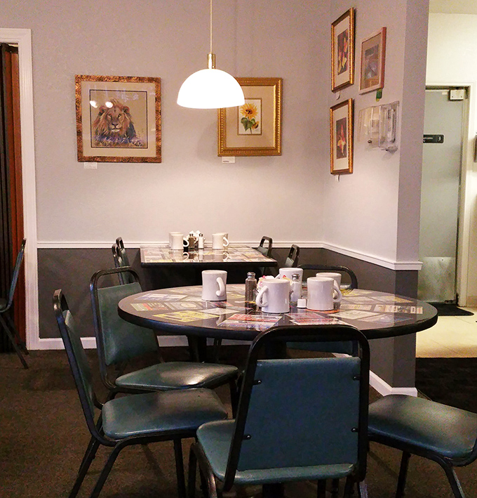 Cozy corner tables where coffee flows freely and conversations meander pleasantly. The framed artwork adds just the right touch of local charm.