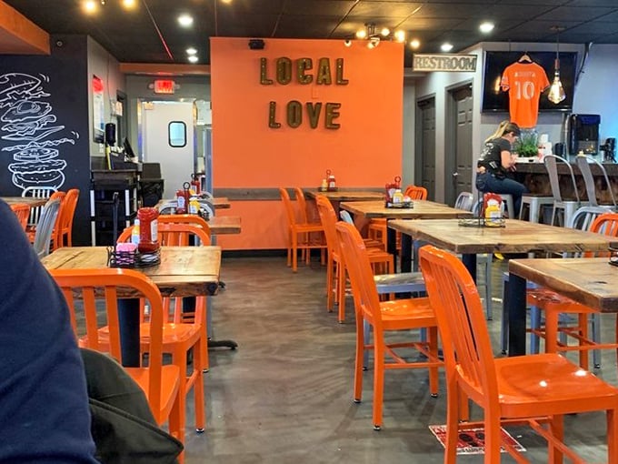 Orange chairs pop against dark walls adorned with "LOCAL LOVE" &ndash; a restaurant that wears its heart on its sleeve and its burgers.
