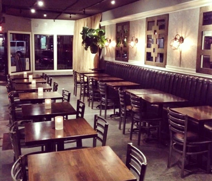 Evening ambiance done right &ndash; simple wooden tables, banquette seating, and just enough lighting to see your food without losing the mood.