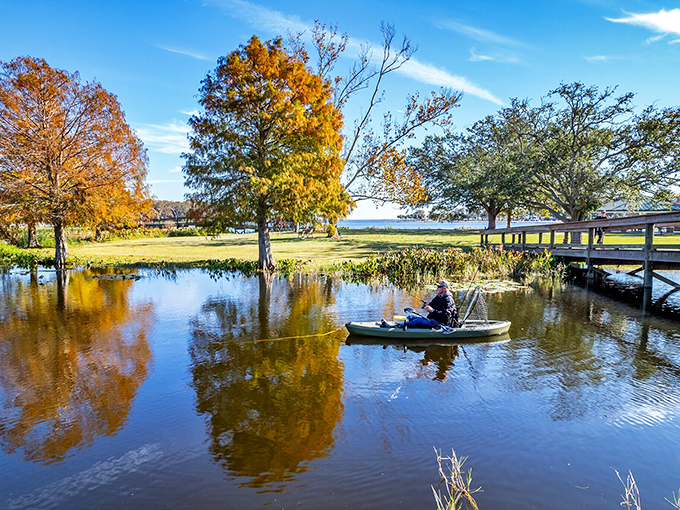 Fall foliage reflected in calm waters as a lone angler drifts by &ndash; proving Florida has seasons, they're just more subtle than their northern cousins.