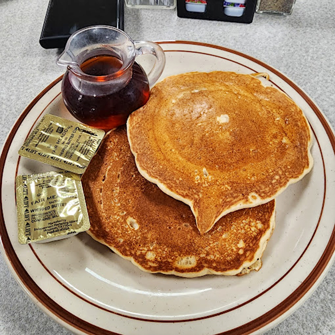 Pancakes golden as a Nebraska sunset, with butter melting into those perfect divots. Breakfast architecture at its finest.