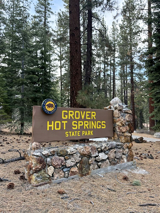 The park entrance sign, built of stone and wood, stands as a rustic welcome mat to California's natural hot tub experience.