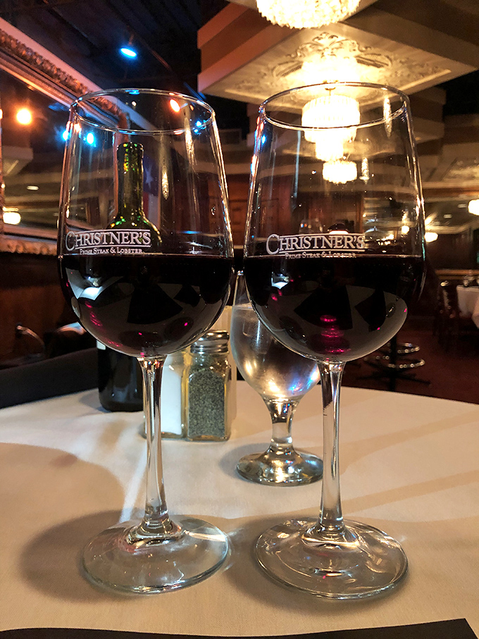Two glasses of red wine catching the chandelier's glow&mdash;a toast to decisions well made in an evening that's just beginning to unfold.
