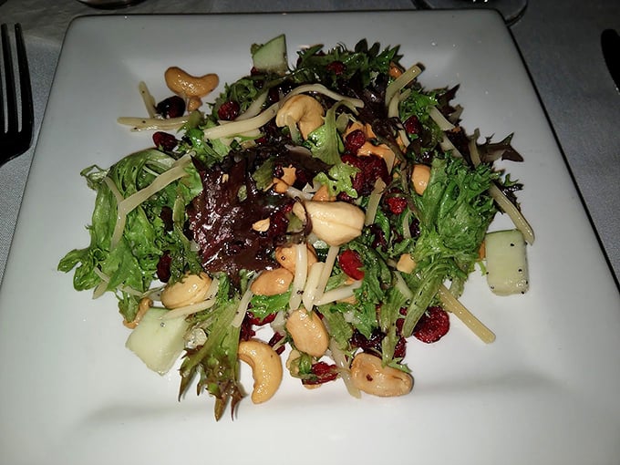 A salad that's having more fun than most entrees&mdash;mixed greens dancing with cranberries, cashews, and what appears to be apple slices.