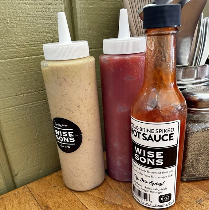 Condiment bottles standing at attention like delicious soldiers. The house-made pickle brine hot sauce adds a kick that would make your bubbe raise an eyebrow&mdash;in approval.