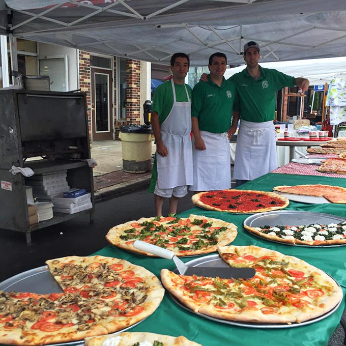The team behind the magic, showcasing their craft at what appears to be a community event with an impressive pizza spread.
