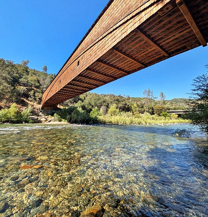 From below, the bridge's underside reveals the genius of 19th-century engineering, with clear waters flowing beneath like nature's own mirror to the past.