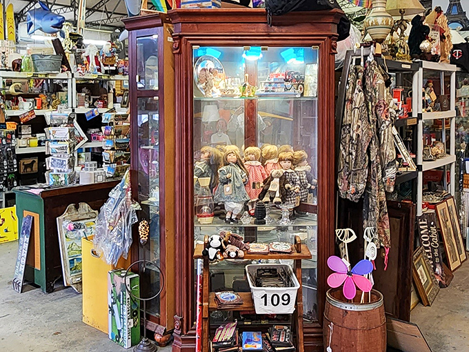 This elegant display cabinet houses porcelain dolls frozen in time, their painted expressions watching shoppers hunt for their own treasures.