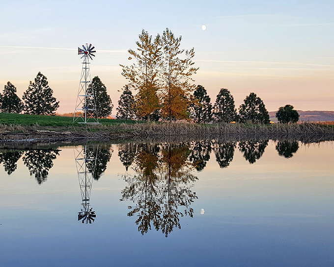 Rural Sheridan showcases Oregon's agricultural beauty, with a windmill reflected perfectly in still waters at sunset.