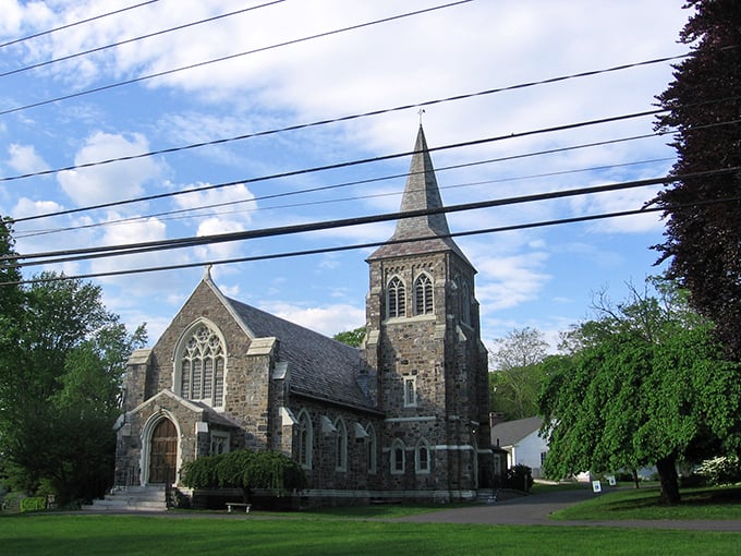 A historic stone church in Washington stands tall with its pointed steeple reaching toward the sky, embodying New England's timeless charm.