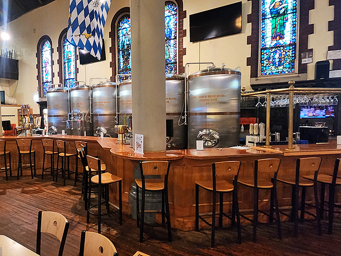 The bar where miracles happen daily. Steel brewing tanks gleam beneath stained glass, a perfect marriage of sacred and secular.