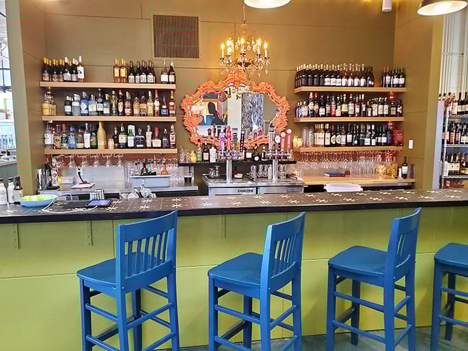 The bar area offers a colorful retreat where bourbon and beer stand ready to complement your smoky feast—liquid courage for tackling that full rack.