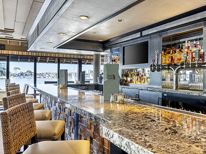 The bar area offers prime seating with bay views, perfect for enjoying cocktails while watching boats drift lazily across the water.