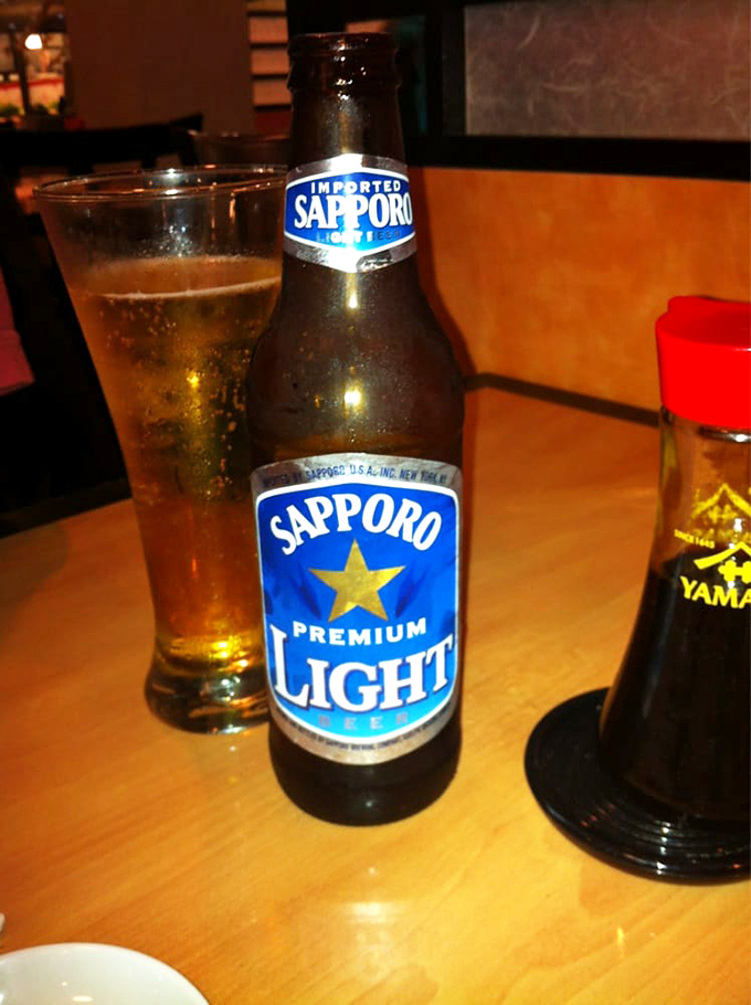 A bottle of Sapporo standing tall like a lighthouse guiding you through a sea of Japanese cuisine.