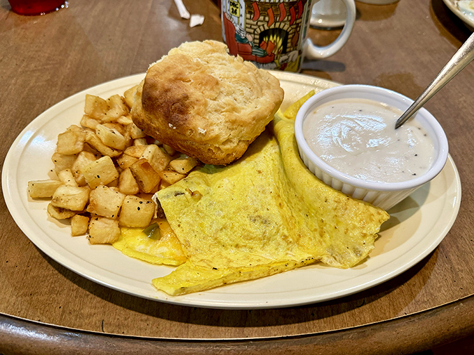 Breakfast perfection on a plate &ndash; golden eggs, home fries with purpose, and a biscuit that could float away if not weighed down by gravy.