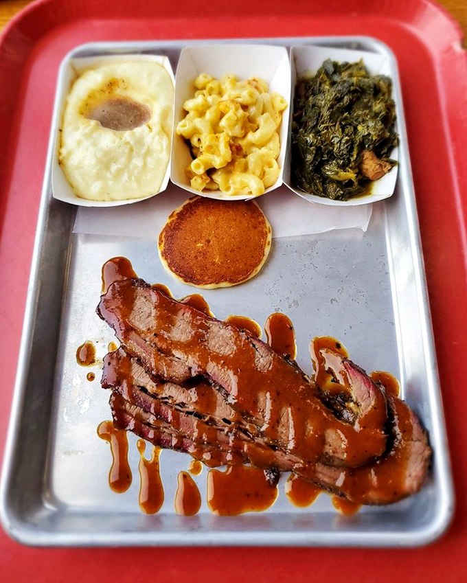 Brisket bathed in gravy alongside mac and cheese, greens, and cornbread&mdash;a meat-and-three symphony on a cafeteria tray.
