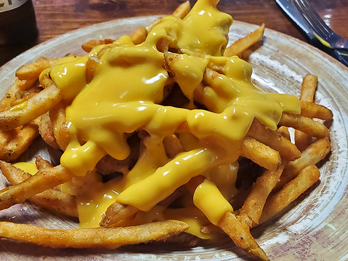 Cheese sauce cascading over fries like a delicious yellow waterfall – this is what dreams are made of.