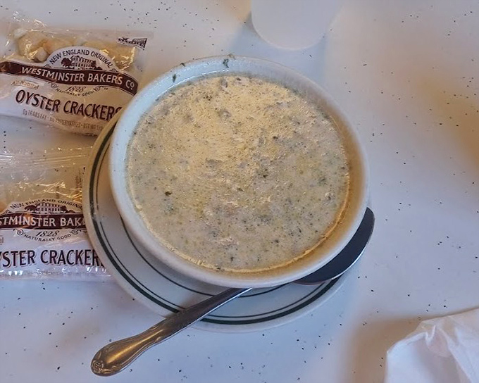 A bowl of New England clam chowder with Westminster oyster crackers standing by &ndash; creamy, briny comfort in every spoonful.