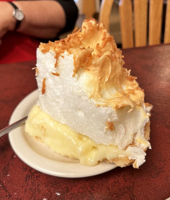 A slice of coconut cream pie wearing a meringue hat so tall it needs its own zip code. Cloud-like, yet somehow substantial.