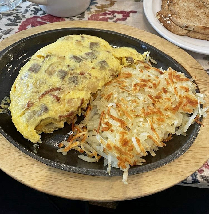 An omelet that's achieved perfect fluffiness alongside hash browns with that ideal crispy-to-tender ratio. Breakfast harmony on a plate.