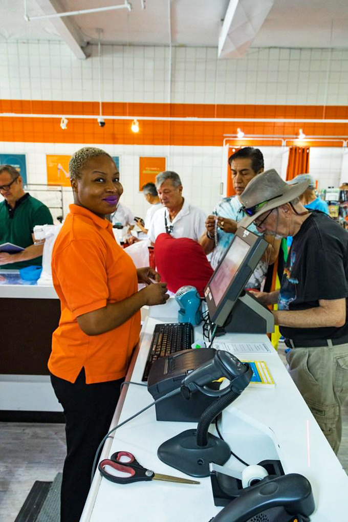 The image shows the checkout area with staff assisting customers.