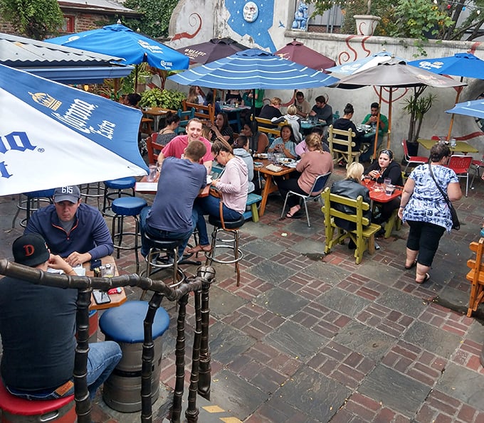The outdoor courtyard buzzes with energy as diners gather under blue umbrellas, creating a communal atmosphere that feels like Philadelphia's best backyard party.