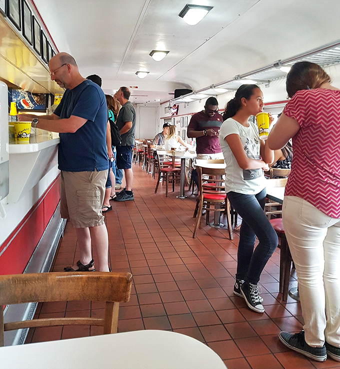 The narrow dining car creates an intimate experience where strangers become temporary neighbors united by the universal language of great food.