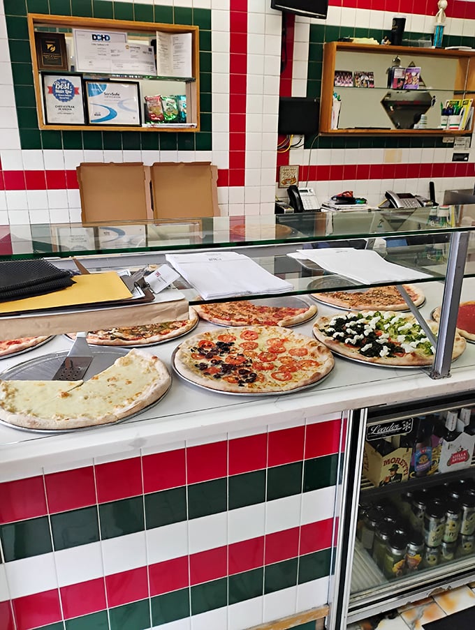 Behind the counter, where pizza dreams come true—the display case showcasing today's offerings like precious jewels under glass.