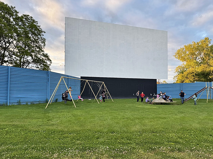 The screen stands sentinel over its grassy kingdom, where children frolic and adults reminisce about simpler entertainment times.