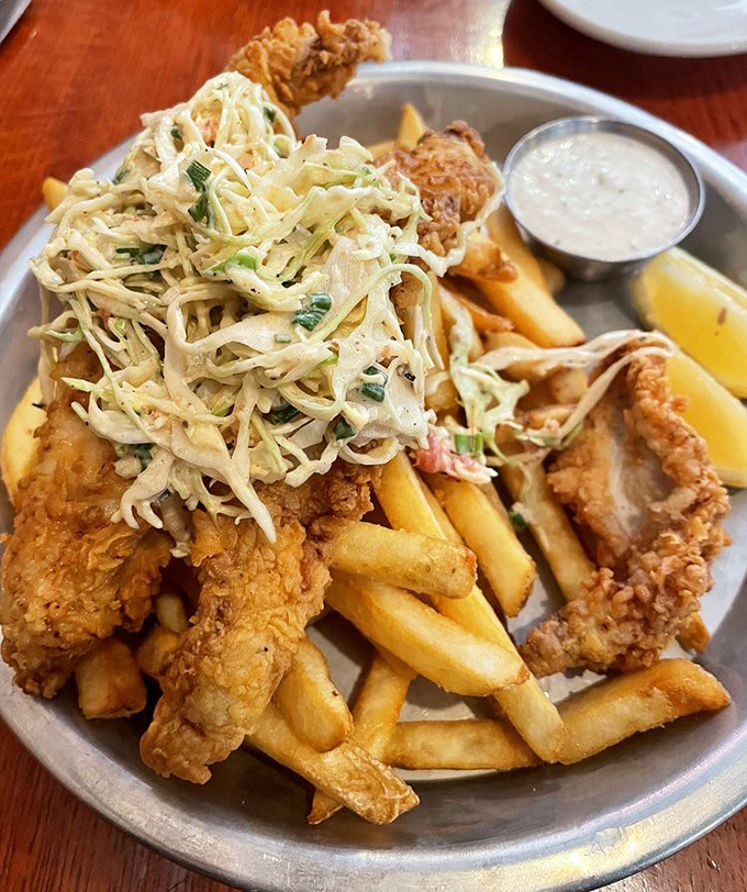 Crispy fish nestled among golden fries and topped with a mountain of slaw&mdash;a plate that makes you want to high-five the chef. 
